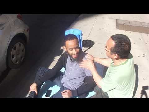 Luodong Massages Black Man's Shoulder On The Sidewalk
