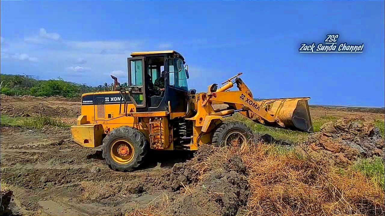 The loader dredges the wavy land and piles it into the sunken ground ...