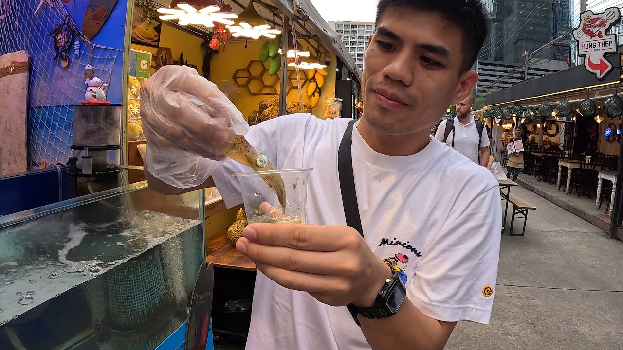 Eating live squid 🦑 shot at Jodd Fairs night market in Bangkok Thailand ...
