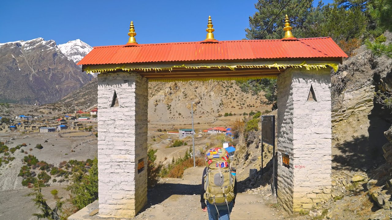 Trekker walking through traditional village entrance gates high in the ...