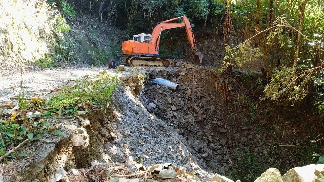 Abandoned Excavator rebuilding washed out road and installing new ...