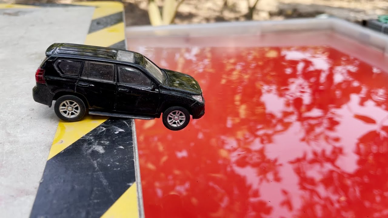 Various small diecast model cars moving and falling into the red water ...