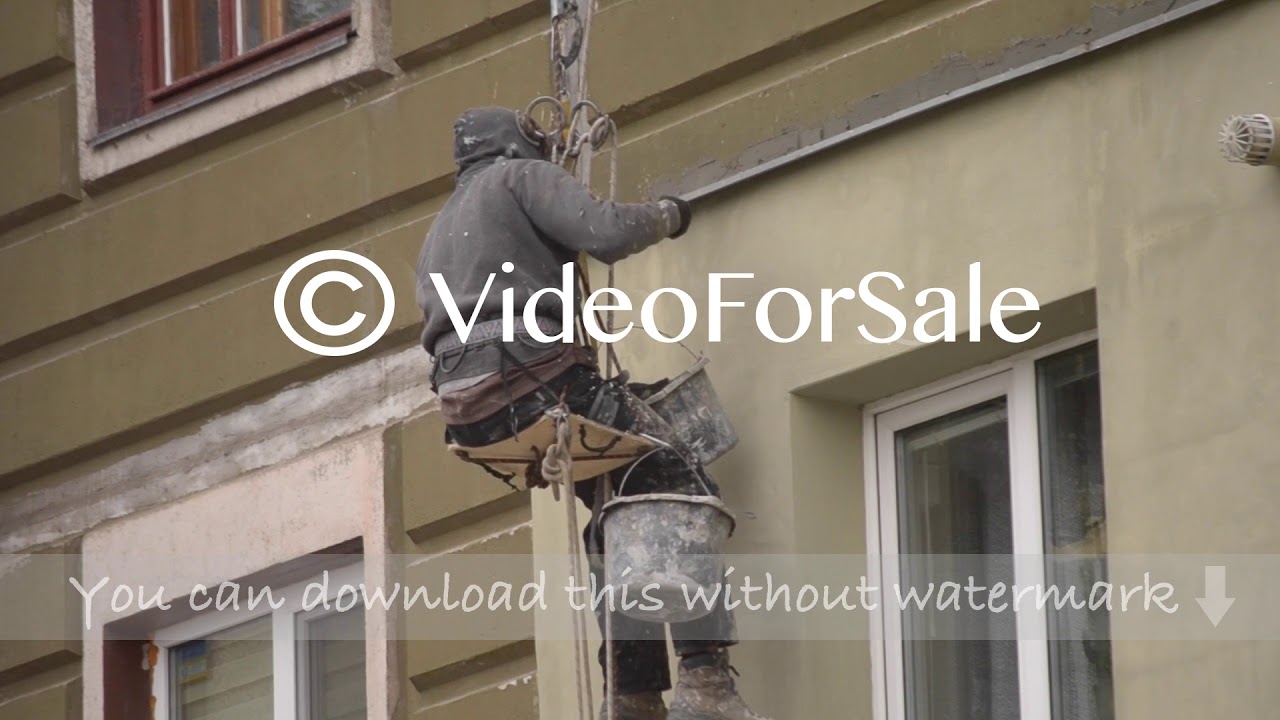 The man works on high-rise works cladding, plastering of the house ...