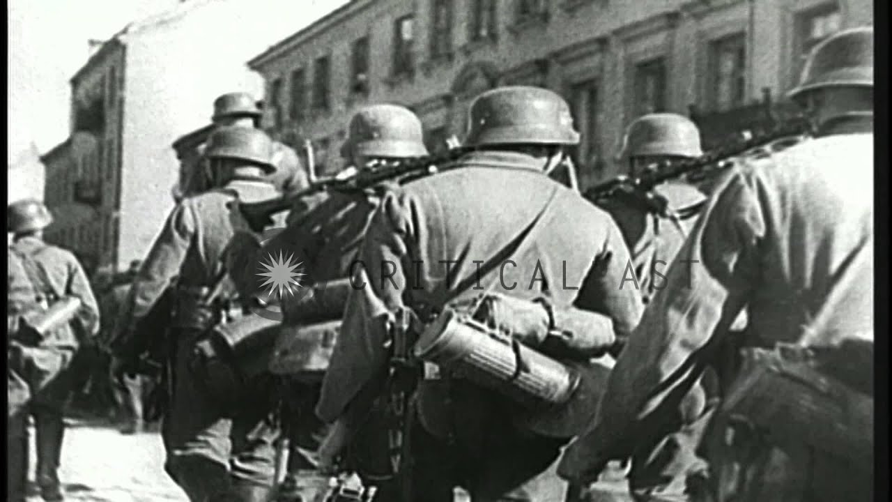 German soldiers march in a town and carry ammunitions on military vans ...