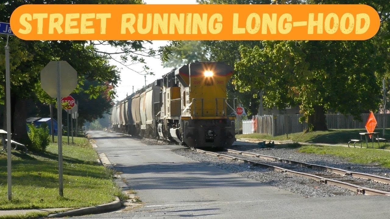 Street running Long-hood forward with a 108 car train in busy town ...