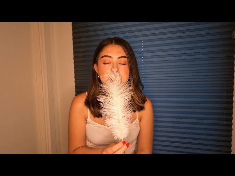Beautiful girl teasing her nose with a big feather and sneezing