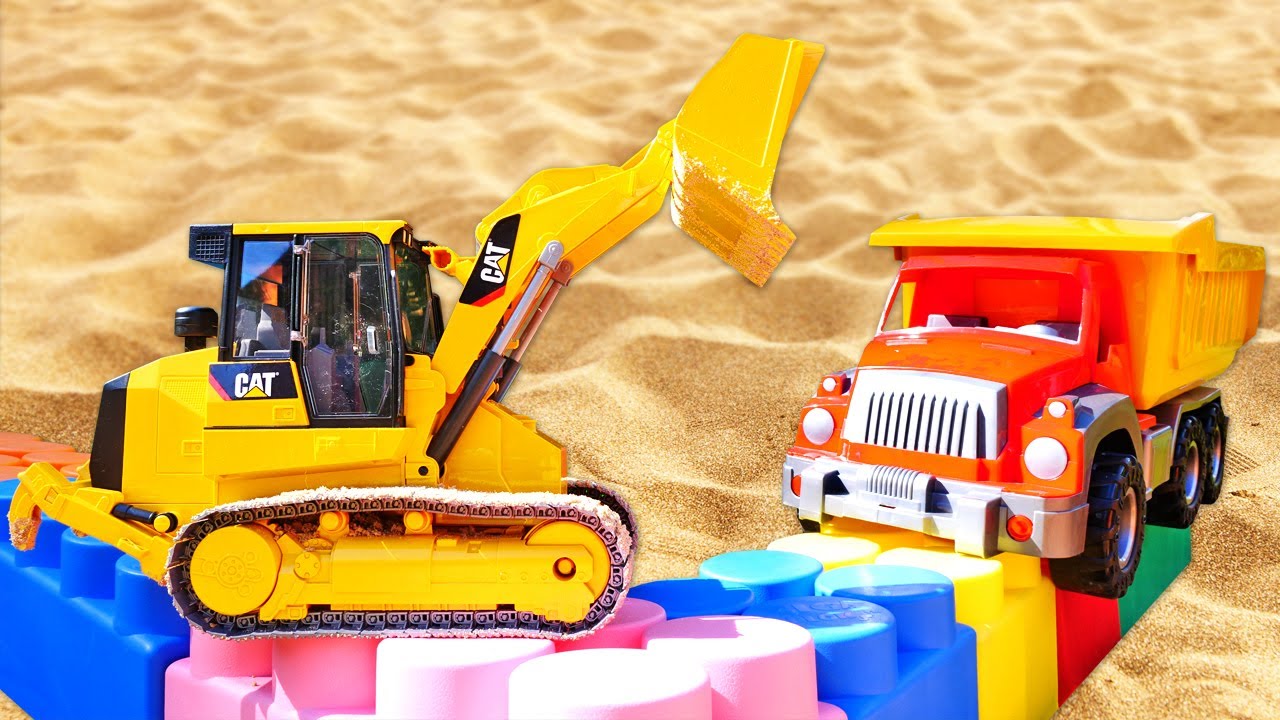Der Bagger und der Kipplaster bauen einen Sandkasten. Spaß für Kinder ...