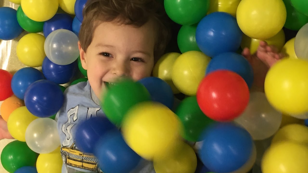 TODDLER HAVING FUN AT AN INDOOR PLAY CENTER. Ball pit, bouncy house ...