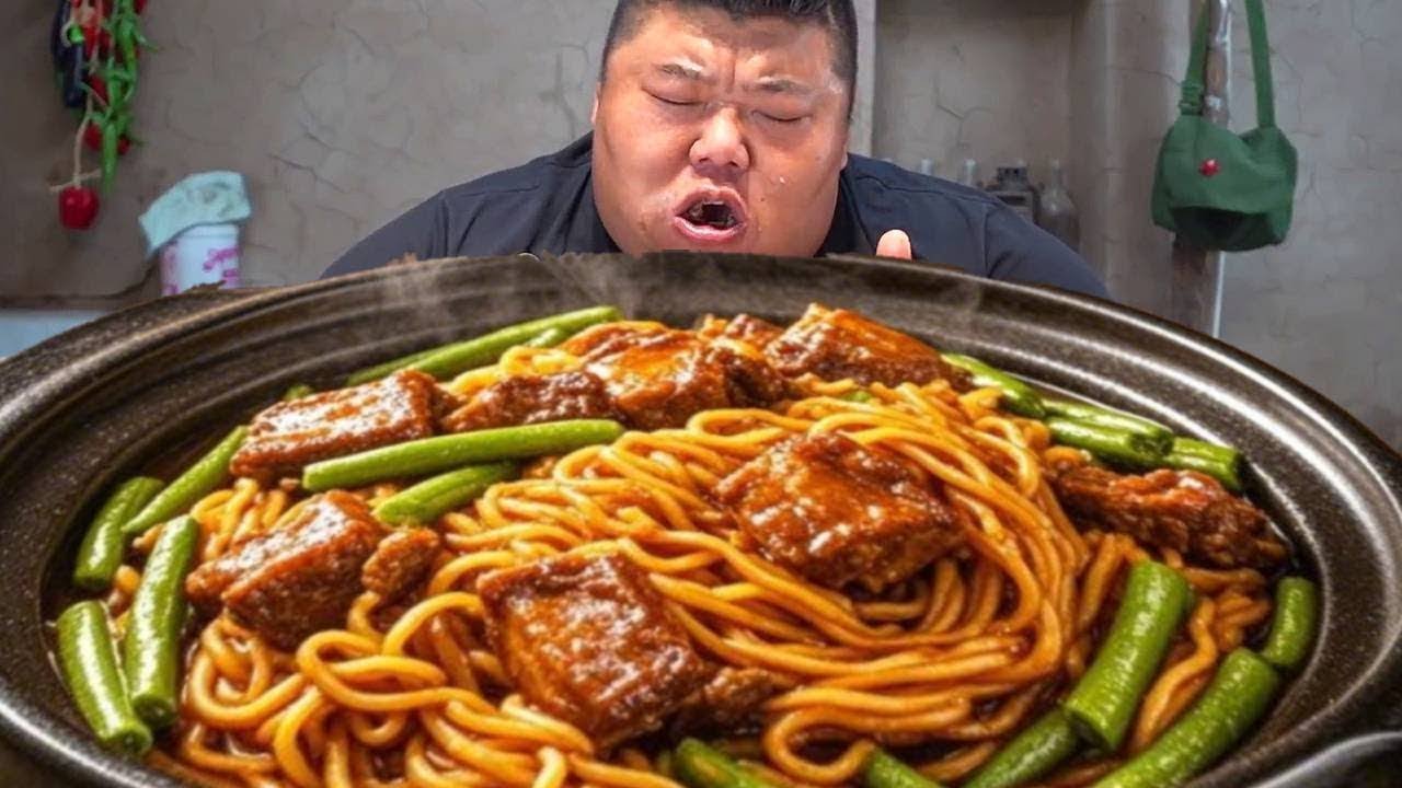 Braised pork ribs noodles in a big iron pot, served with garlic, it’s ...