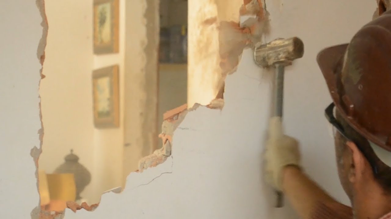 Demolisher demolishing wall in house with hammer - YouTube