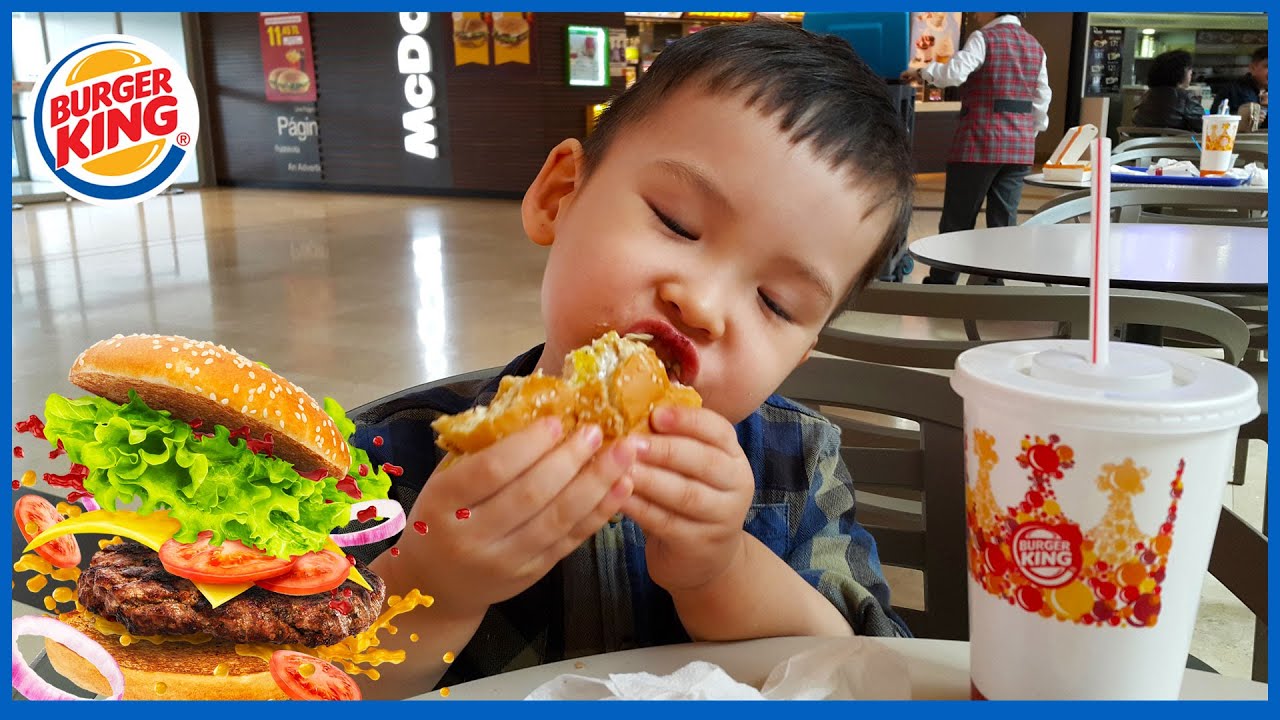 A child biting a burger. Ready to eat. Toddler kid looking at a big ...