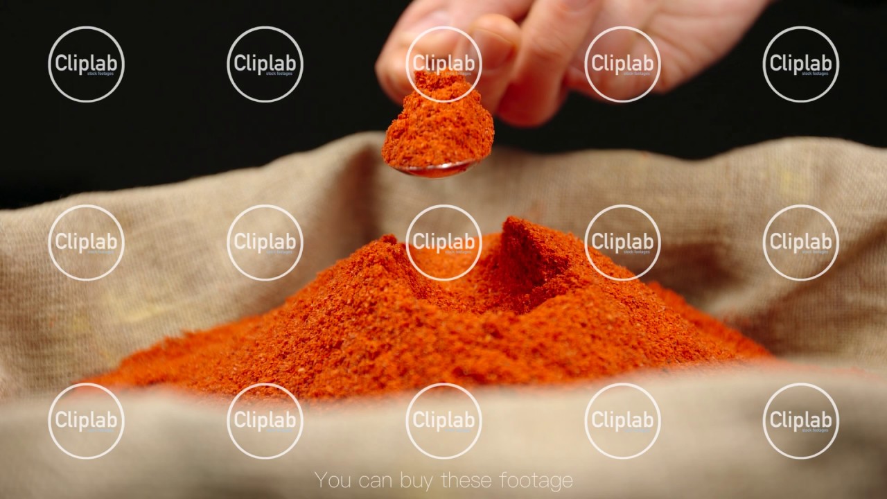 Human hand takes a pinch of a red pepper powder by a spoon from a top ...