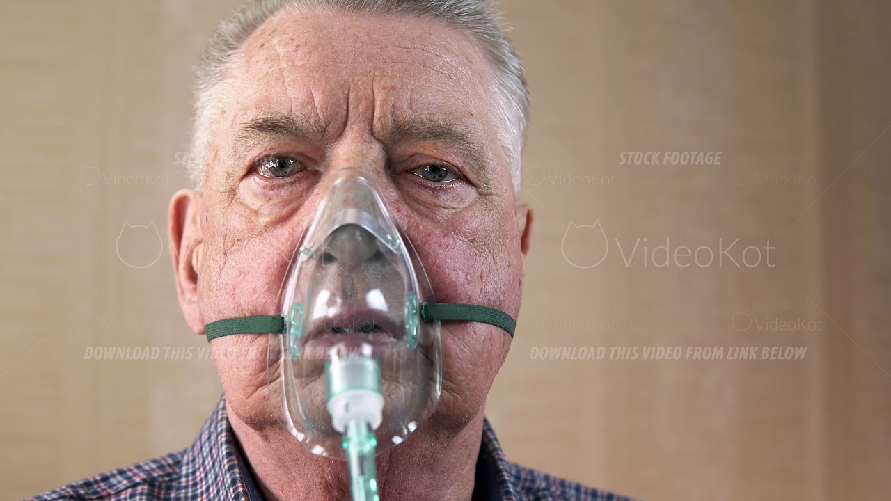 Portrait of an elderly man with COPD in an oxygen mask is breathing ...