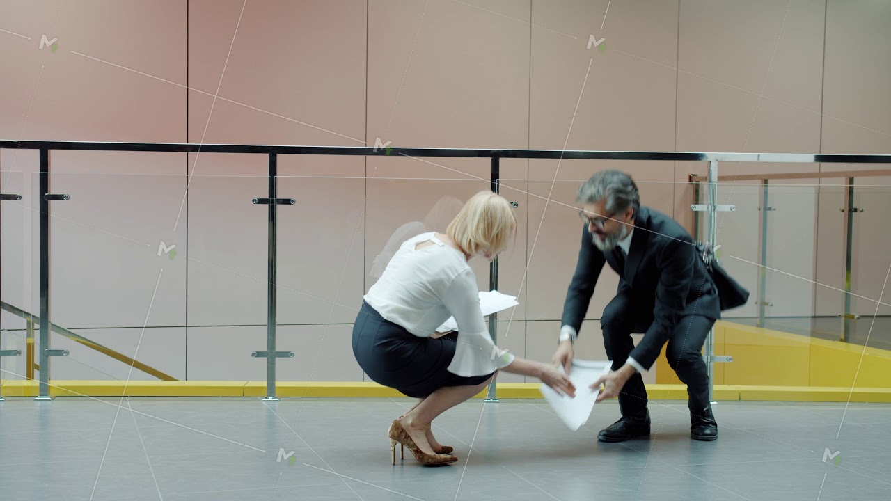 Mature office workers bumping by accident in hall shaking hands talking ...