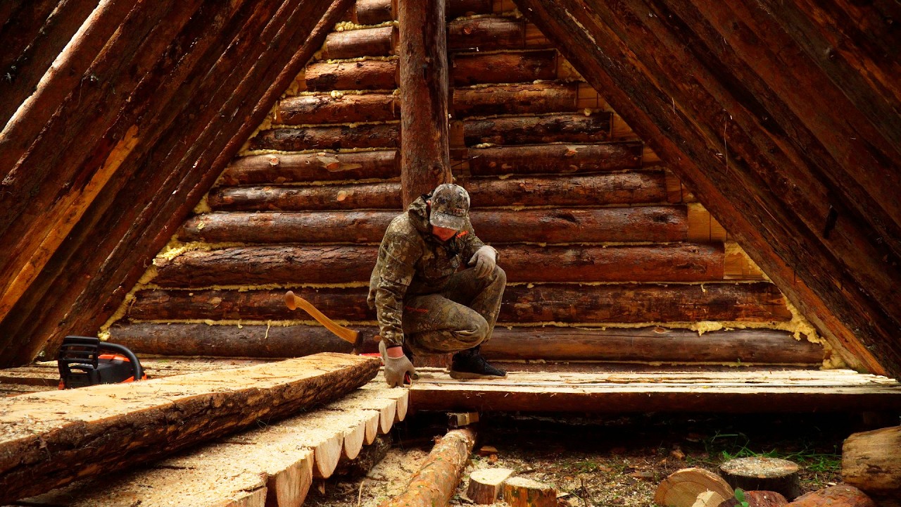 A MAN ALONE BUILDS A LARGE LOG HOUSE IN THE WILD FOREST. THE WOODEN ...