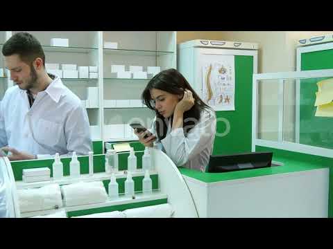 Bored Young Pharmacist Broqsing via Mobile Phone at Work Place | Stock ...