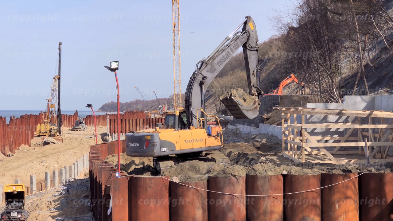 Excavator works on the seashore, strengthening the Baltic Sea coastline ...