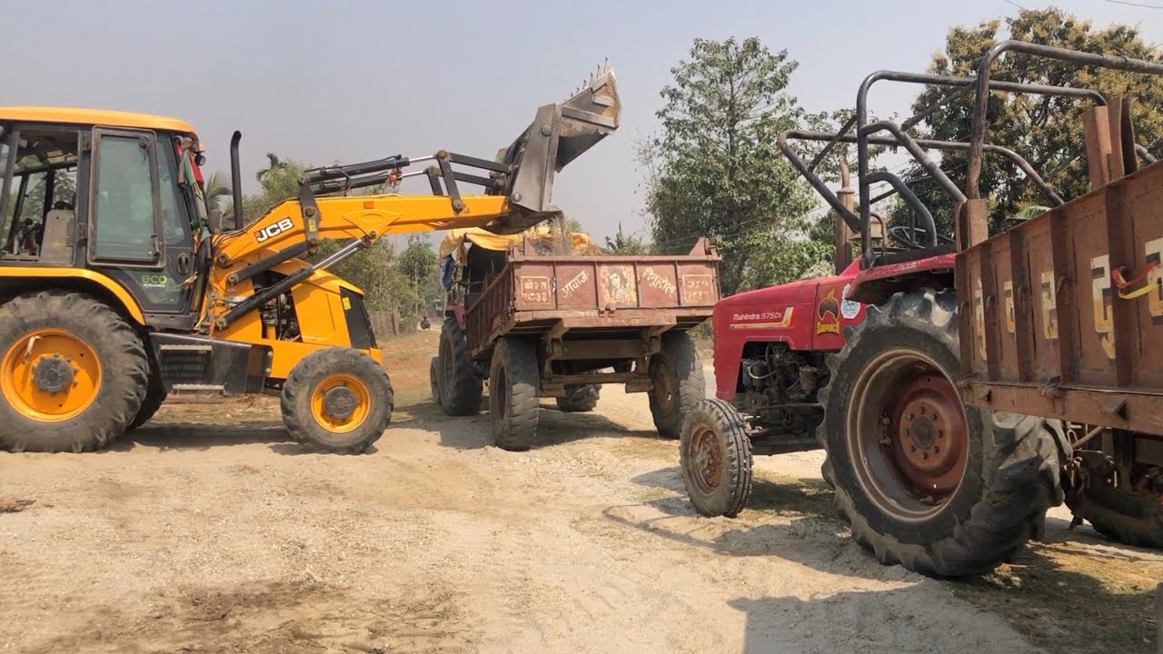 A JCB Backhoe Machine Loading Sand Onto Two Mahindra Tractors ...