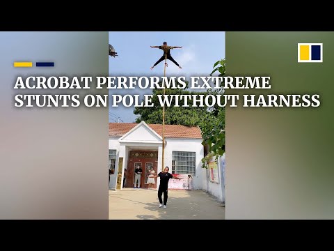 Acrobat performs extreme stunts on pole without harness