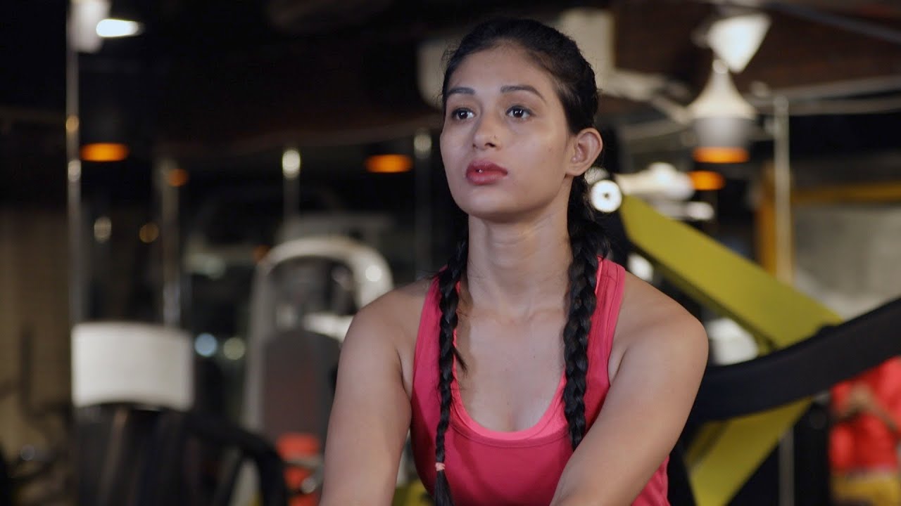 Young Indian girl exercising / training on a cycling machine i ...