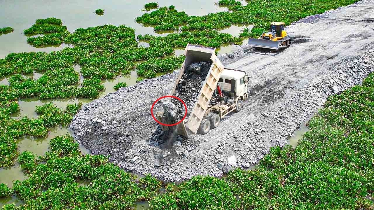 Building road on large river using power equipment, push large rock ...