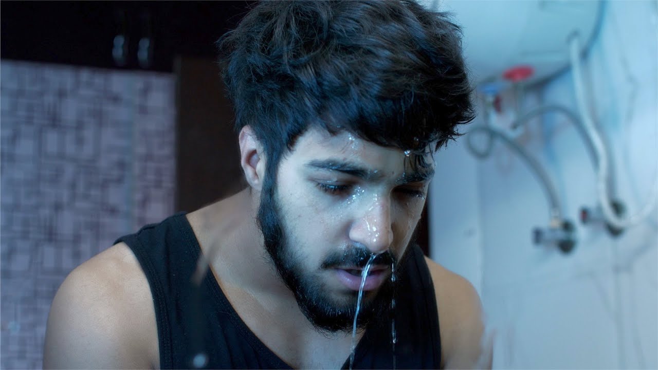 A young Indian boy / man washing his face with water splash in ...