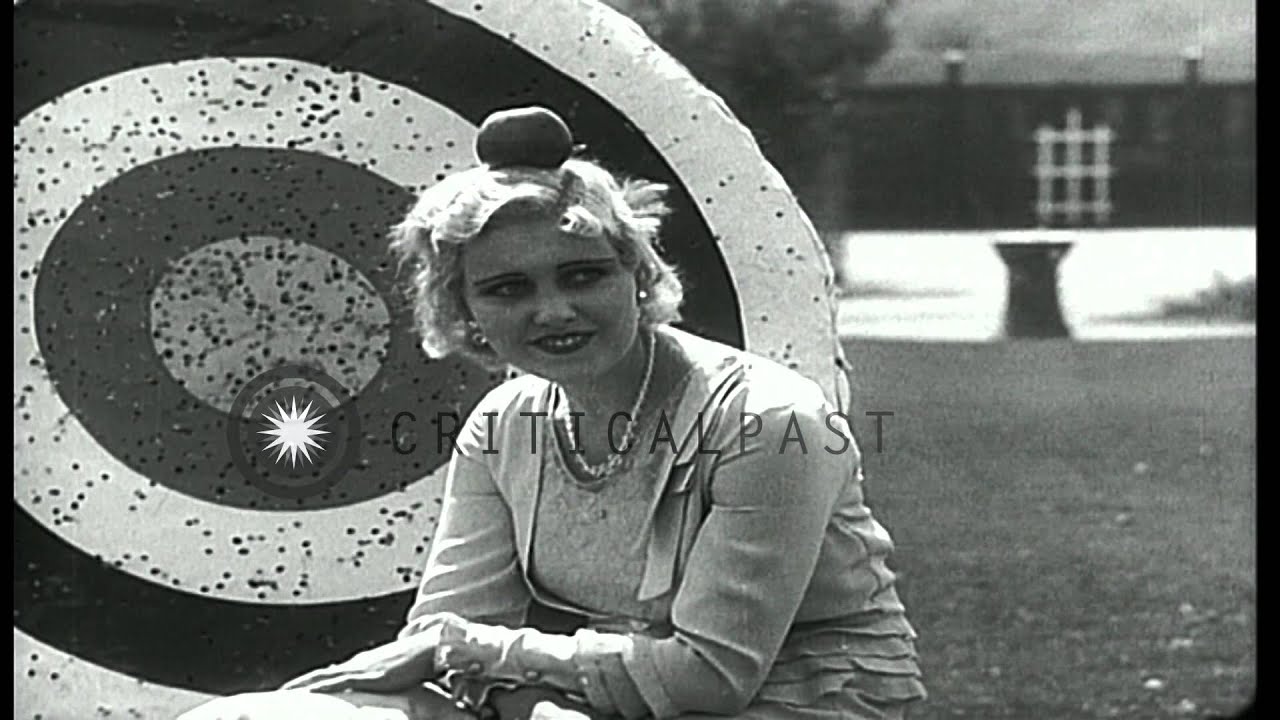 An archer targets an apple on a woman's head, sitting in front of ...