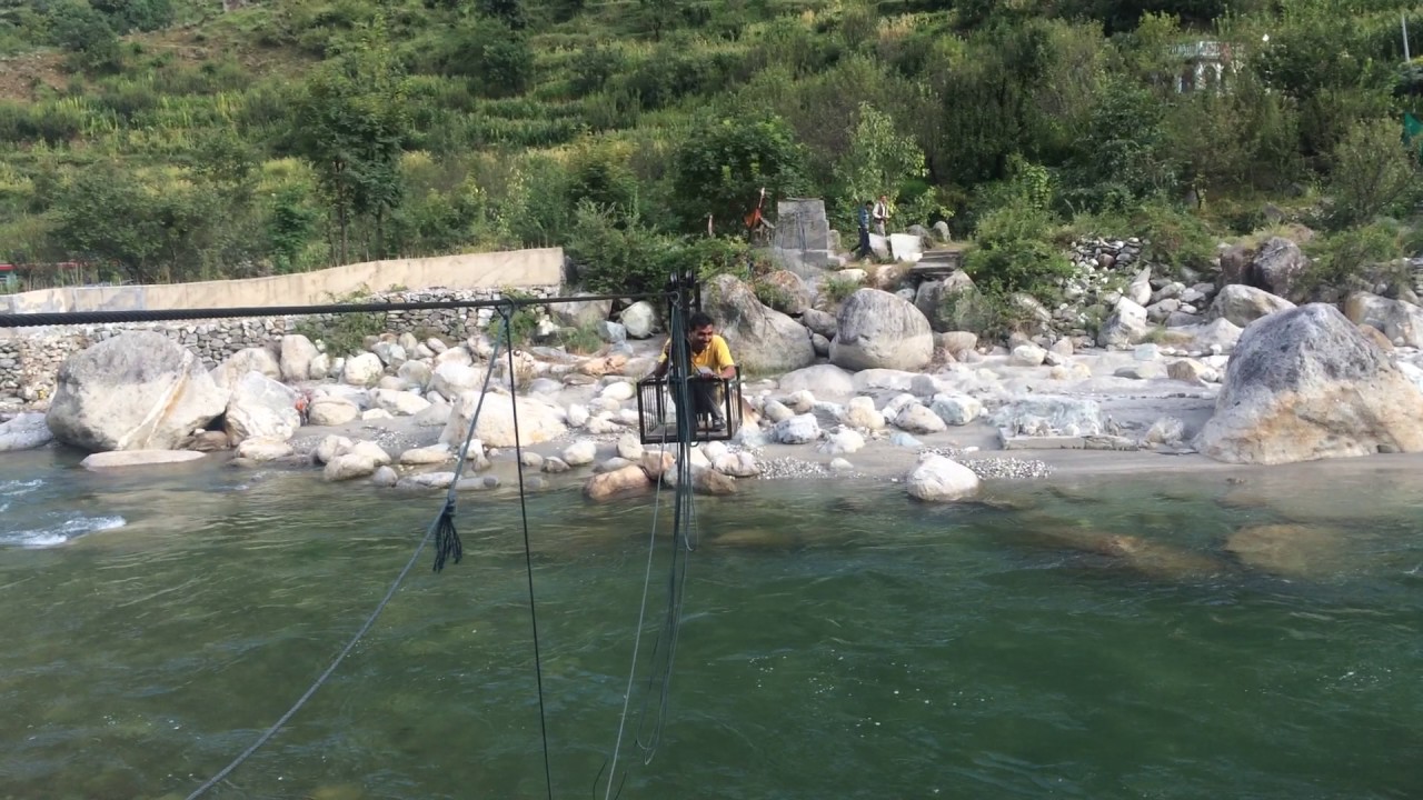 Crossing river using trolley bridge built on a ropeway in Tirthan ...