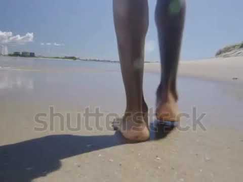 Ebony male soles walk on beach under blue sky