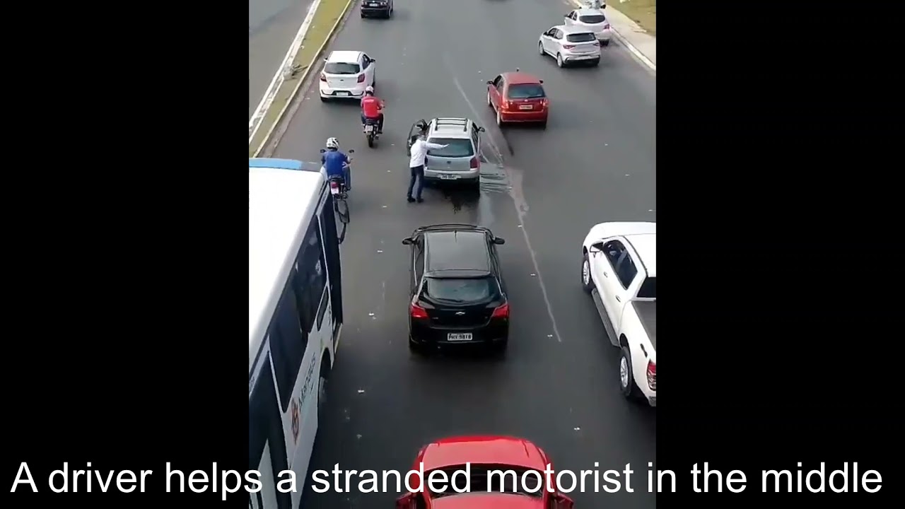 A driver helps a stranded motorist in the middle of a very busy road in ...