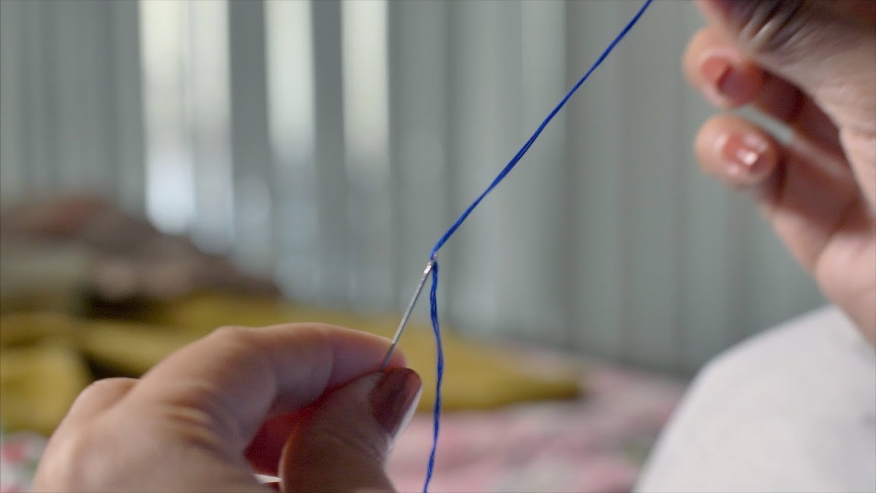 A women / female putting the blue colour thread in a needle | Indian ...