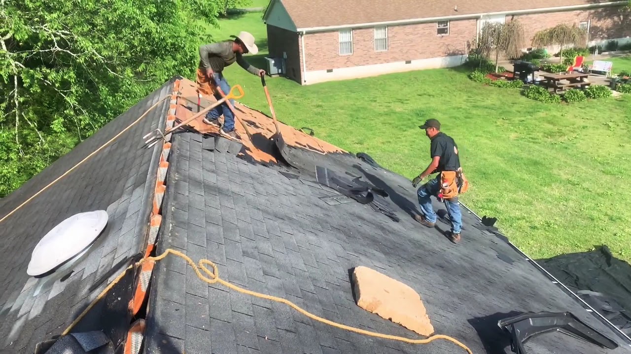 Solid roofing crew in process of tearing a homes roof off in ...