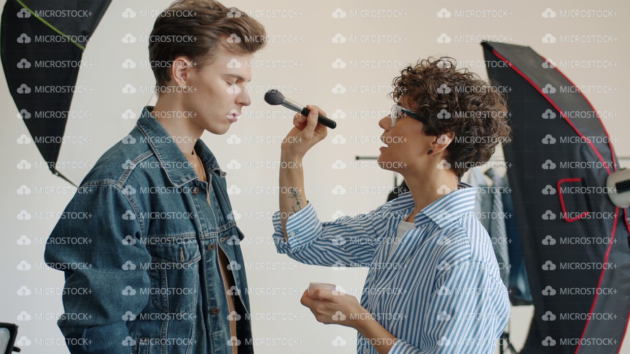 Slow motion of make-up artist beautifying male model in photo studio on ...