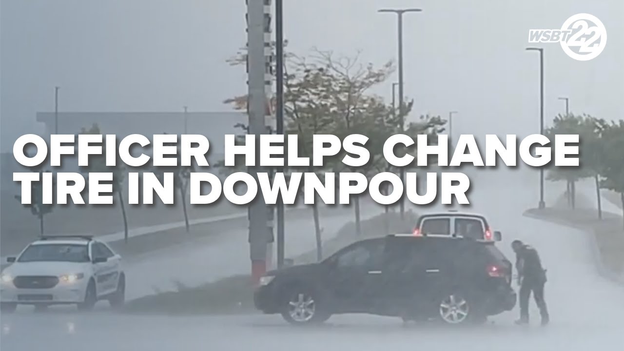 Police officer helps change tire during storms and heavy downpour - YouTube