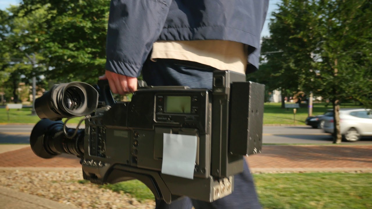 a low angle shot of a cameraman carrying his video camera to a ...