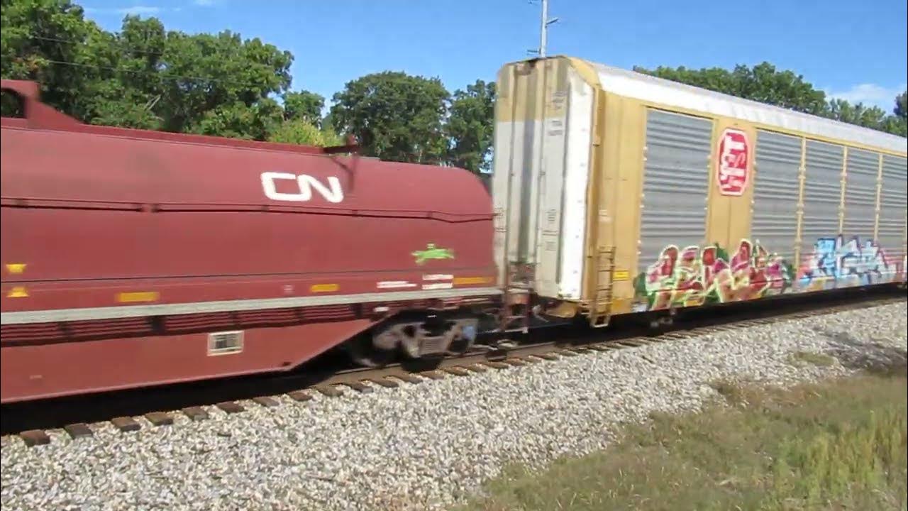 CN 3105, 3975 speed a Westbound freight train with BN hoppers, KCS Multi-Max rack through ...
