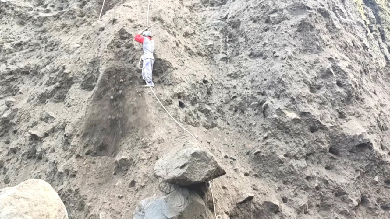 This miner climbs the cliff to get better black sand. - YouTube