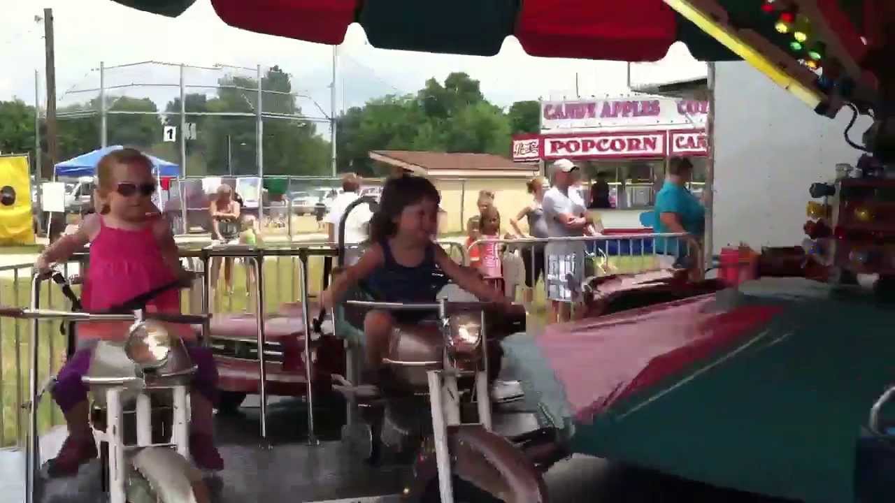 Aurora riding the motorcycle merry go round at the festival. - YouTube