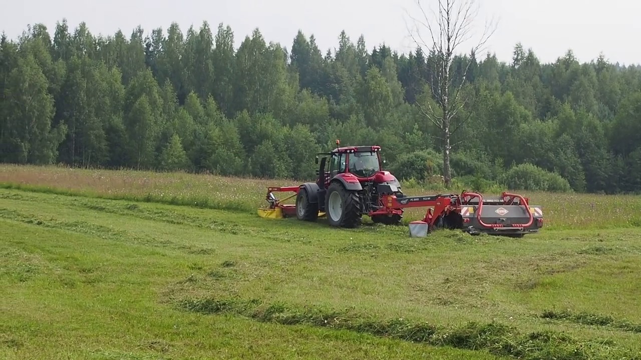 Agricultural trailer mower grass cutting machine in action on the field ...