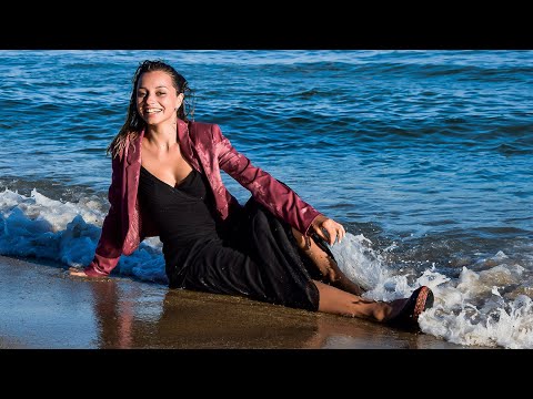 GORGEOUS GIRL AFTER THE PARTY IN A WET EVENING DRESS AND JACKET POSES BY THE SEA FOR WETLOOK VIDEO