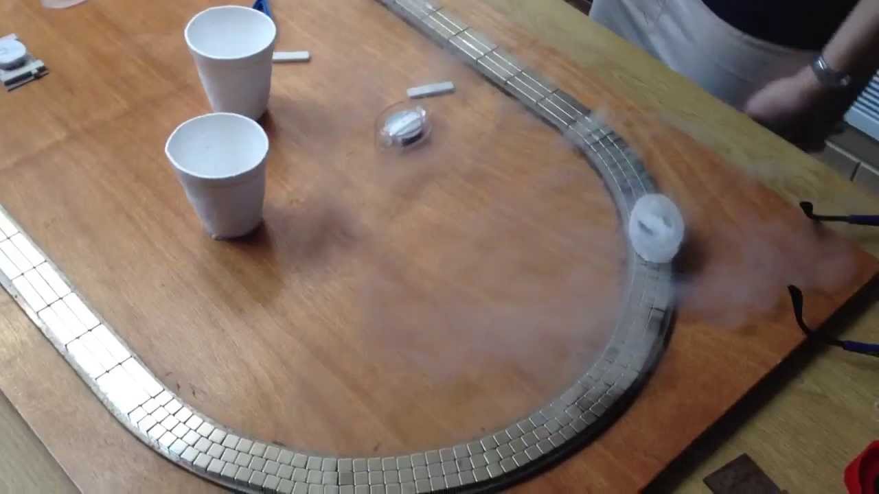 Liquid nitrogen cooled superconductor levitating on a magnetic track ...