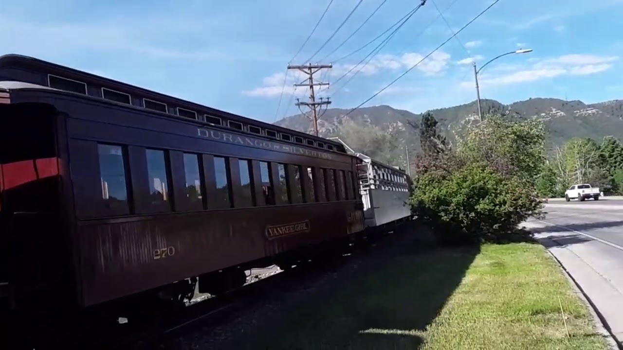 Former D&RGW Locomotive 482 goes around a curve near a road, in Durango ...