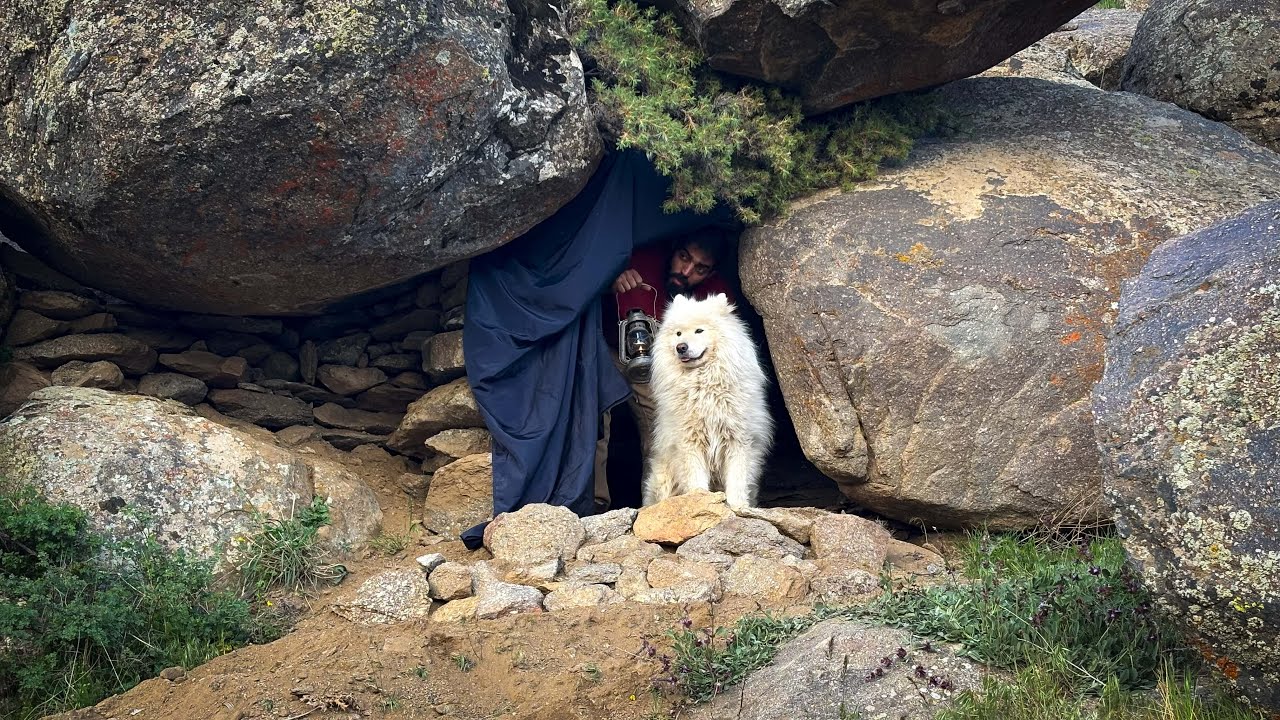 Building a cabin from scratch under a large rock in the mountains ...