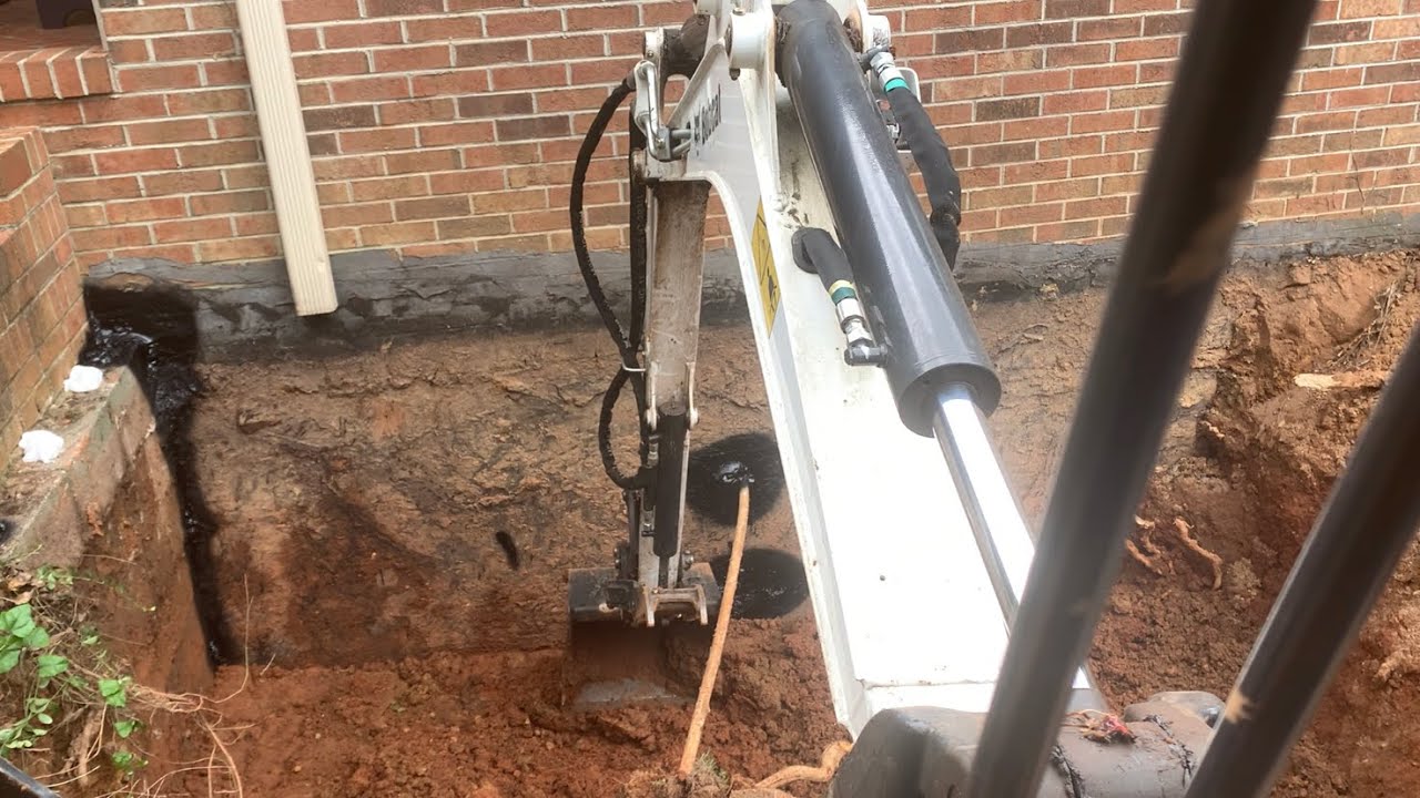 Digging around a foundation with Bobcat E20 - YouTube