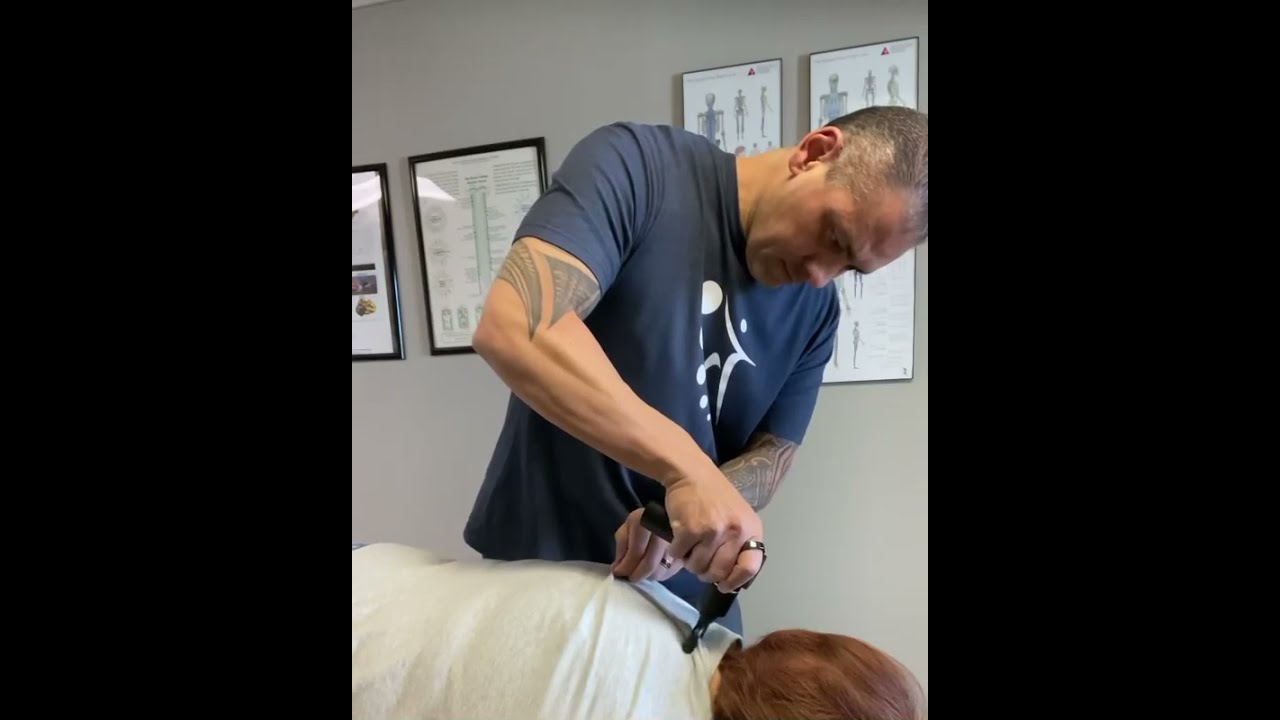 Chiropractor uses the massage gun to help his patients relieve back ...