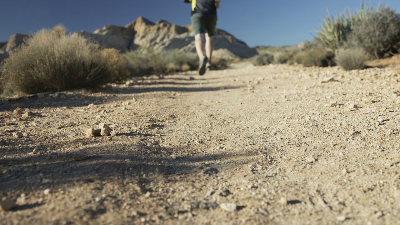 slow motion tilt of man trail running in desert - YouTube