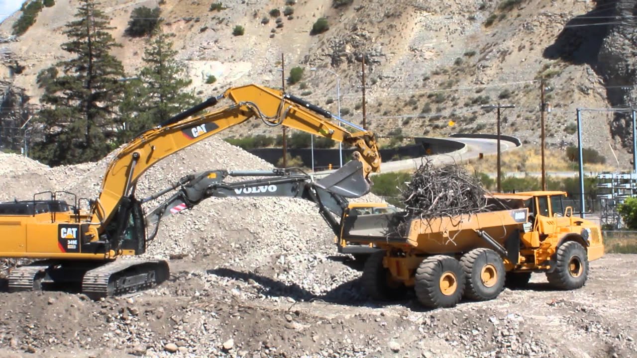 CAT 349E Excavator loading a CAT dump truck with rebar while volvo ...