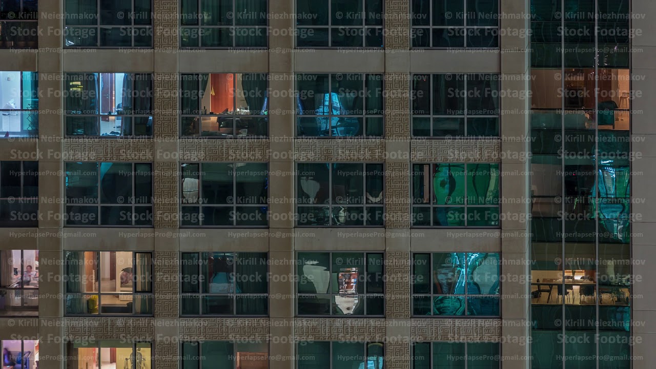 Windows of the multi-storey building with lighting inside and moving ...