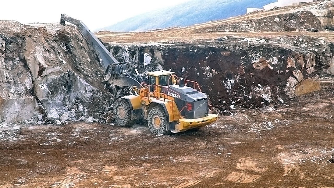 Volvo L350H loader operating with clearing rake in marble quarry - YouTube