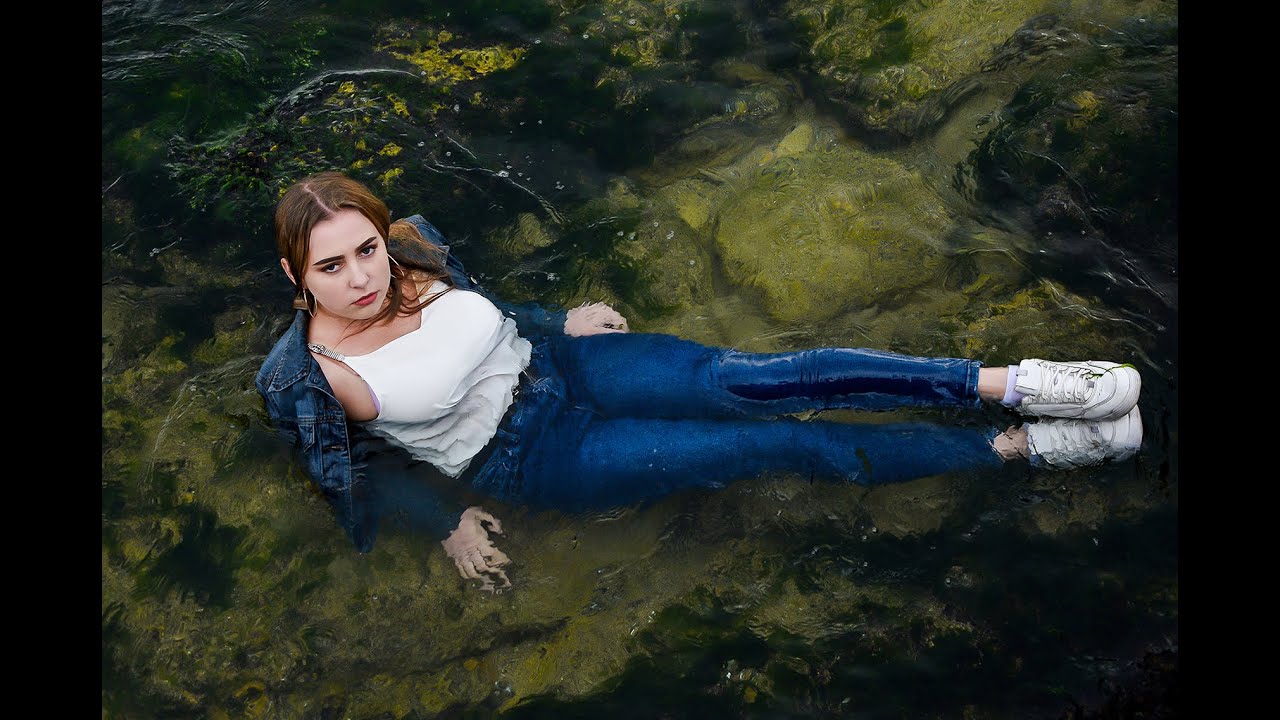 girl in wet denim jacket and wet jeans poses tenderly on the beach by ...